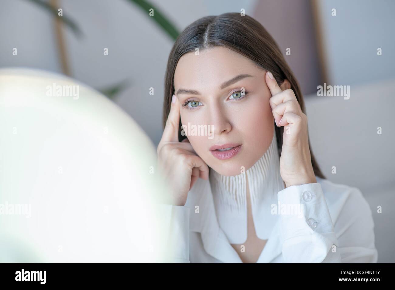 Cute young woman doing face massage and looking relaxed Stock Photo - Alamy