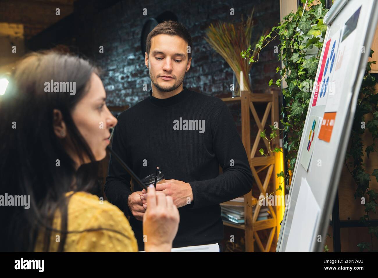 Colleagues working together in modern office using flipchart during ...