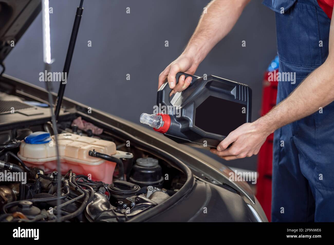 Male hands with canister in open hood of car Stock Photo - Alamy