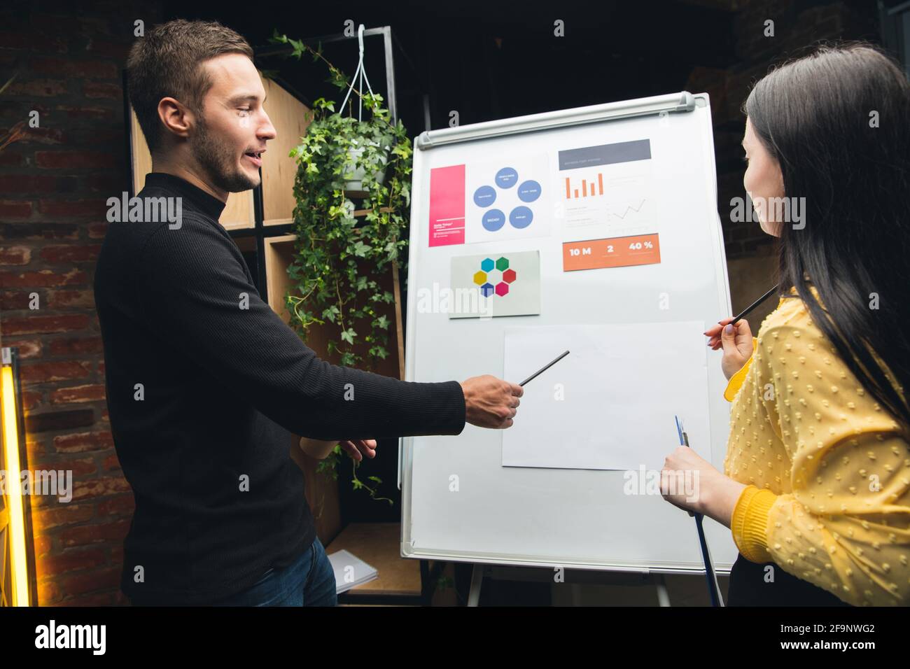 Colleagues working together in modern office using flipchart during ...
