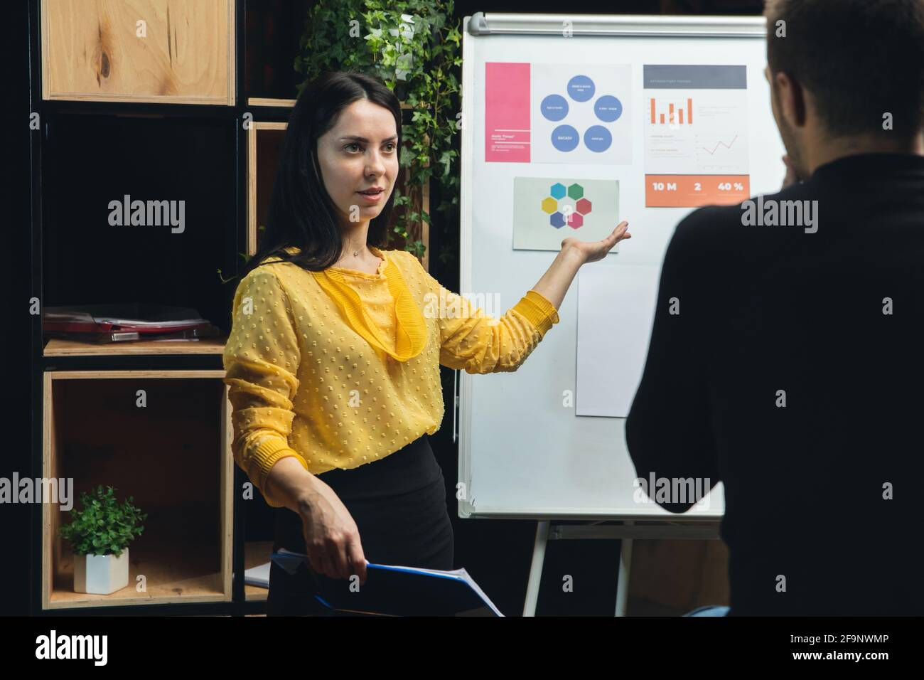 Colleagues working together in modern office using flipchart during ...