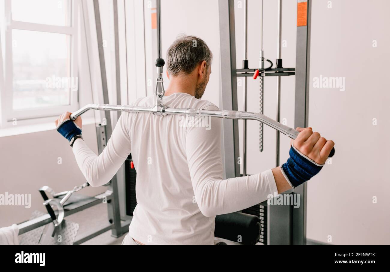 a man performs exercises in the gym on a simulator. back training. rear ...