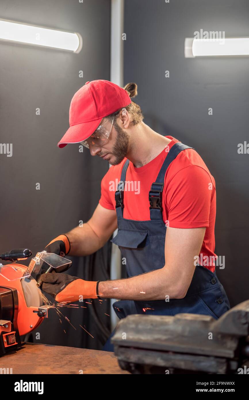 Attentive man machining detail on grinding machine Stock Photo - Alamy
