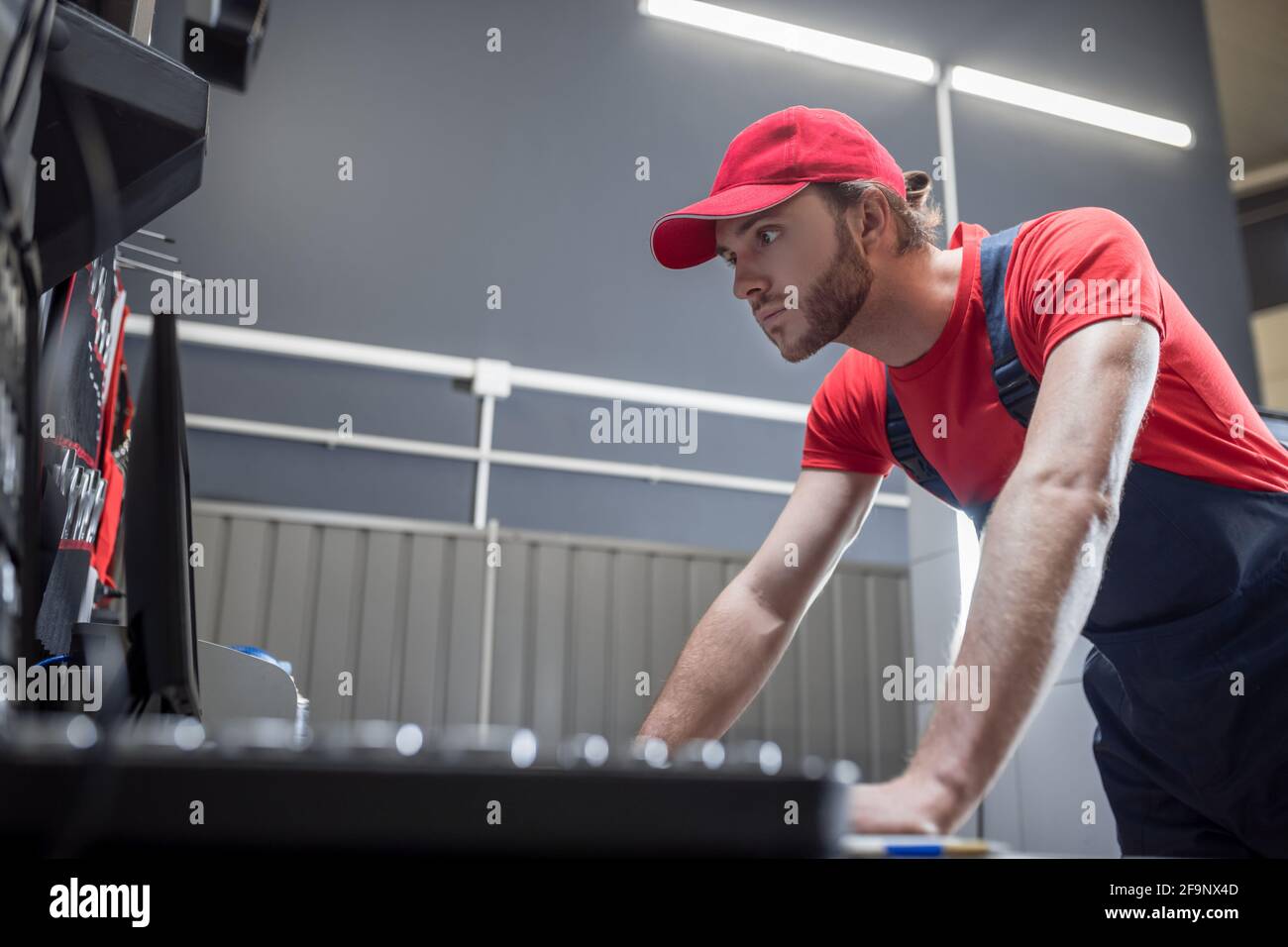 Interested serious man in workwear looking at computer Stock Photo - Alamy