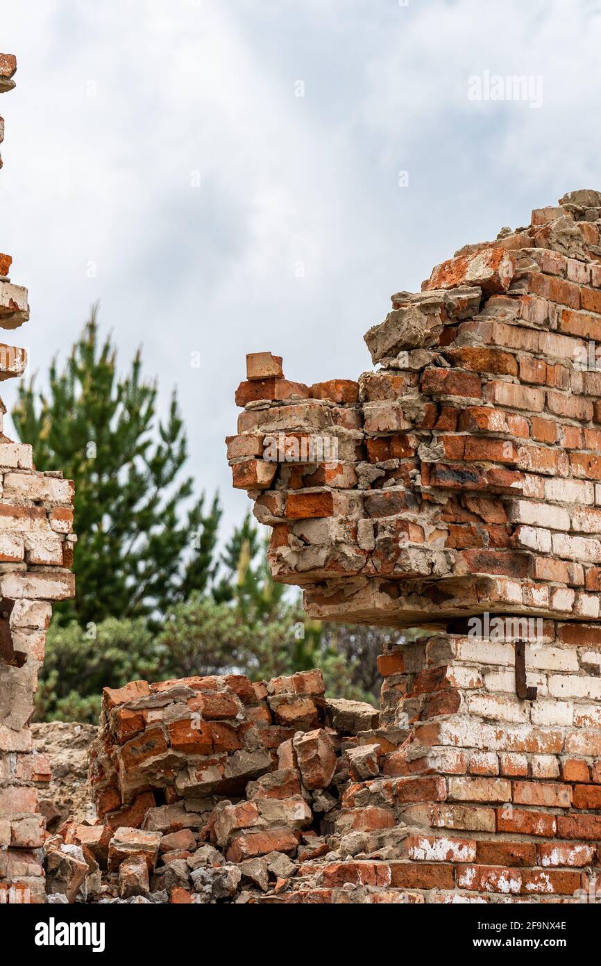 Rift in a brick wall. Close-up. Ruined red brick wall. The wreckage of the wall against the sky ...