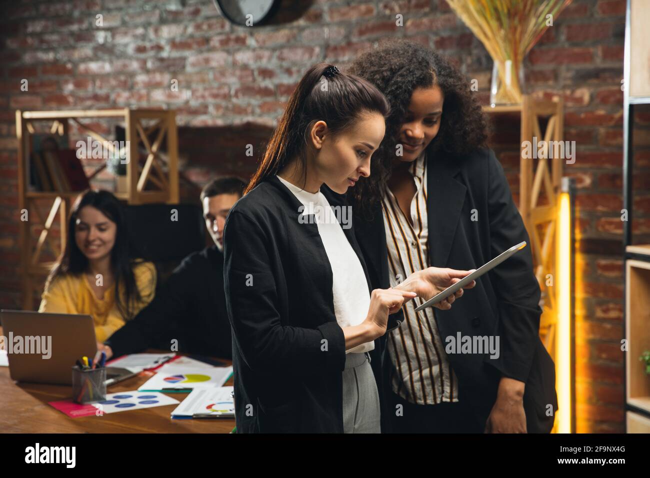 Colleagues working together in modern office using devices and gadgets ...