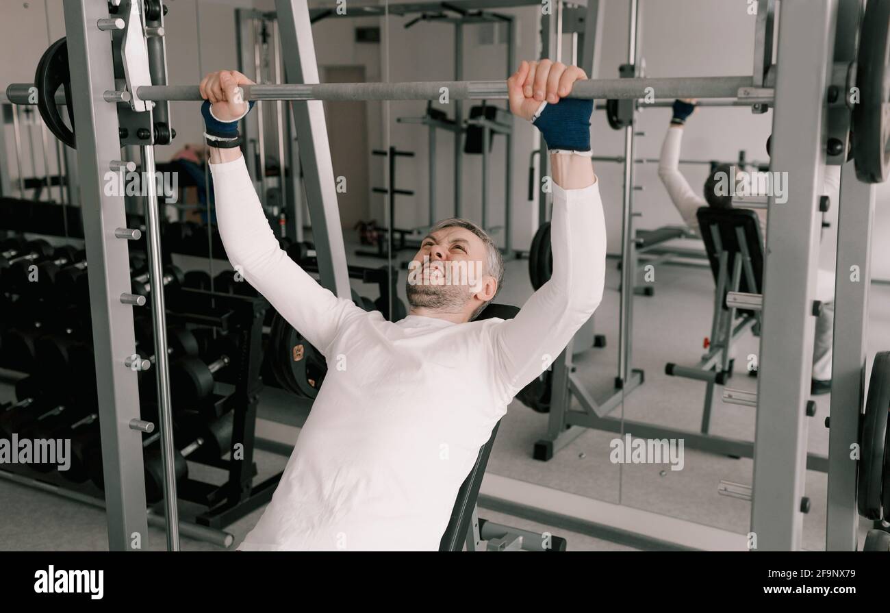 Portrait of a young man doing physical exercises, with a tense face ...