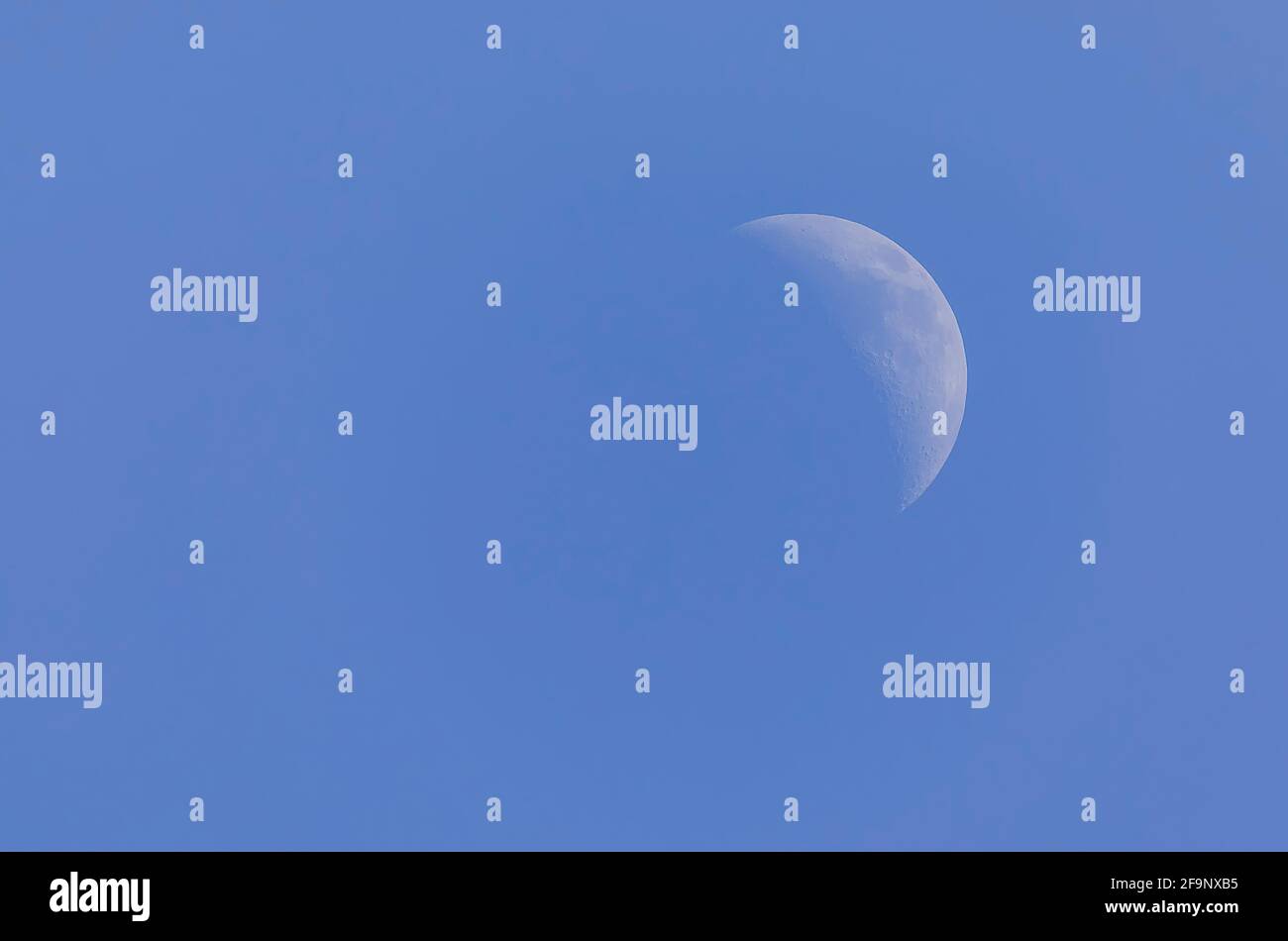 Mid-phase of the moon on a blue sky background Stock Photo - Alamy