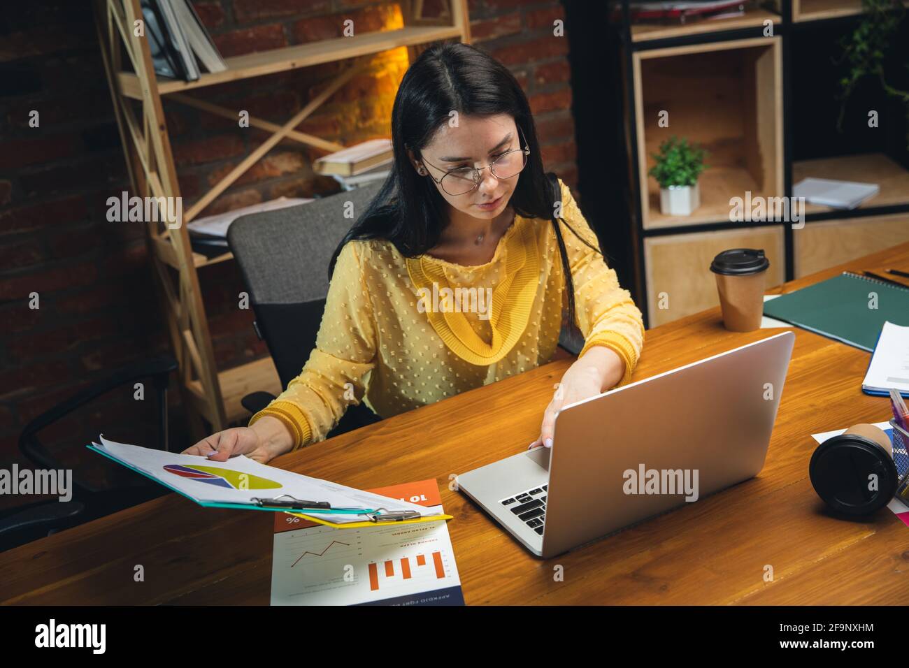 Young woman working in modern office using devices and gadgets. Making ...