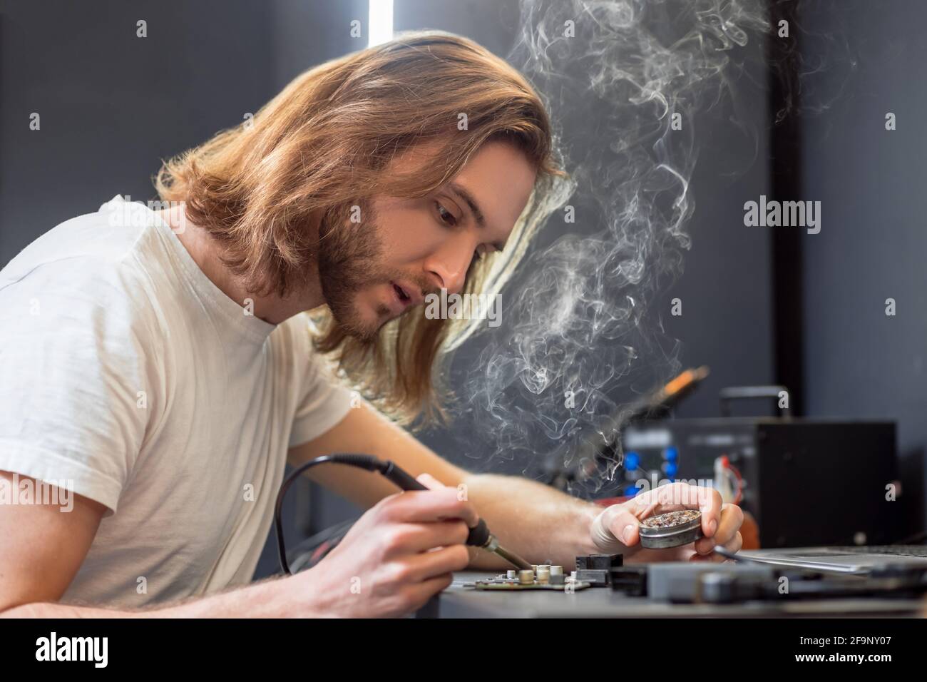 Man with soldering iron and box of solder Stock Photo - Alamy