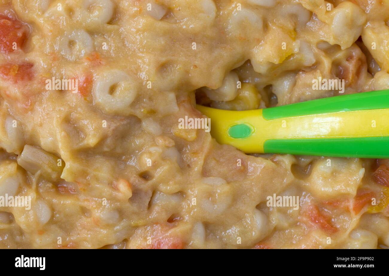 Close view of macaroni and cheese baby food with a spoon in the food ...