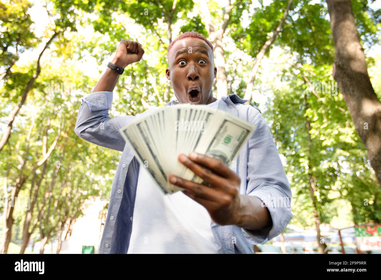 Big win concept. Excited African American guy holding fan of American ...