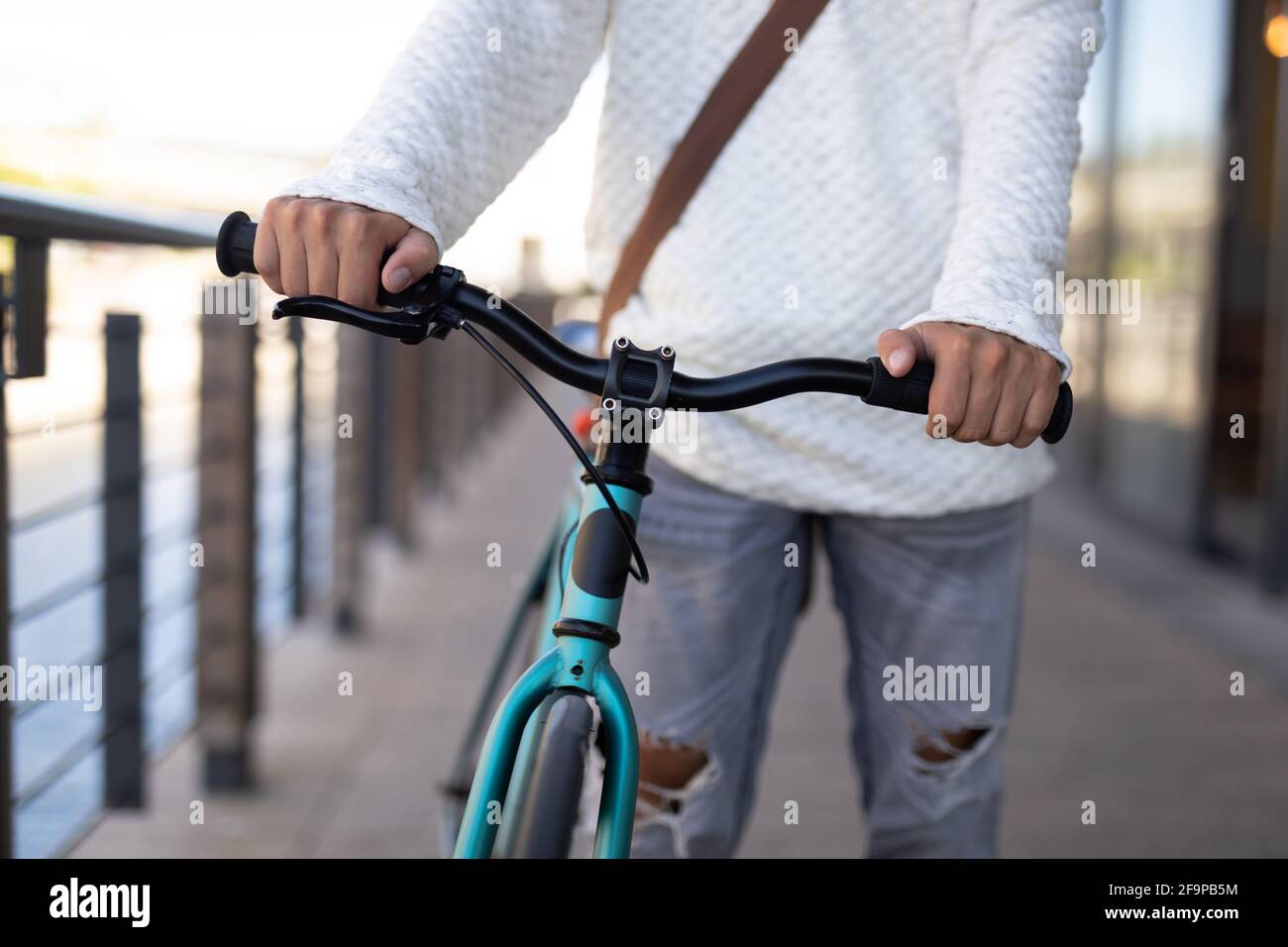 Mid section of mixed race male wheeling bicycle in the street. green ...