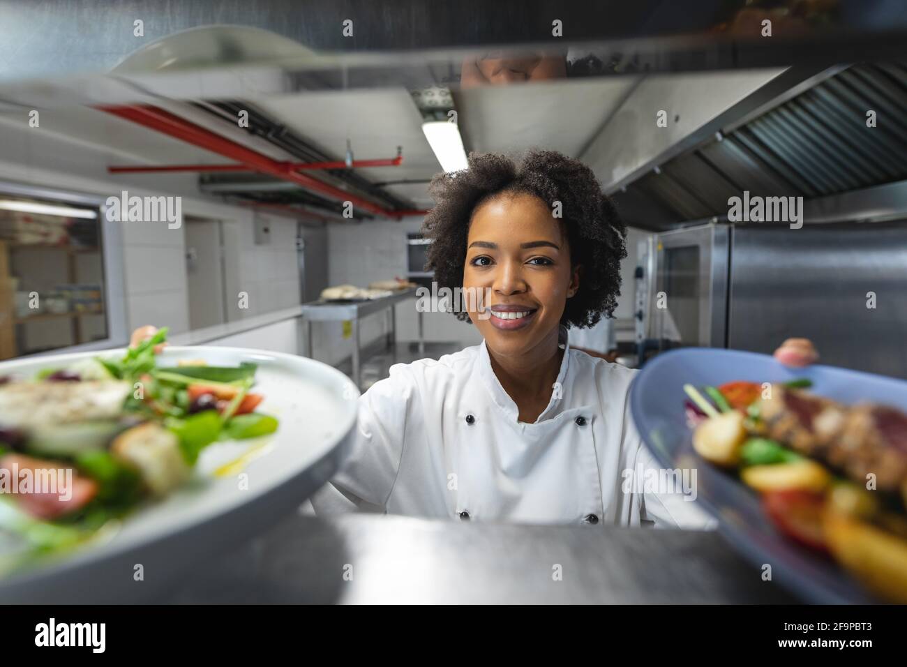Mixed race professional chef giving away dishes to be served with ...
