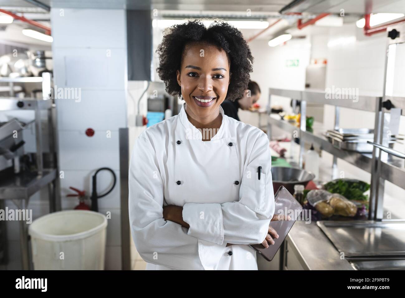 Portrait of smiling mixed race female professional chef with colleagues ...