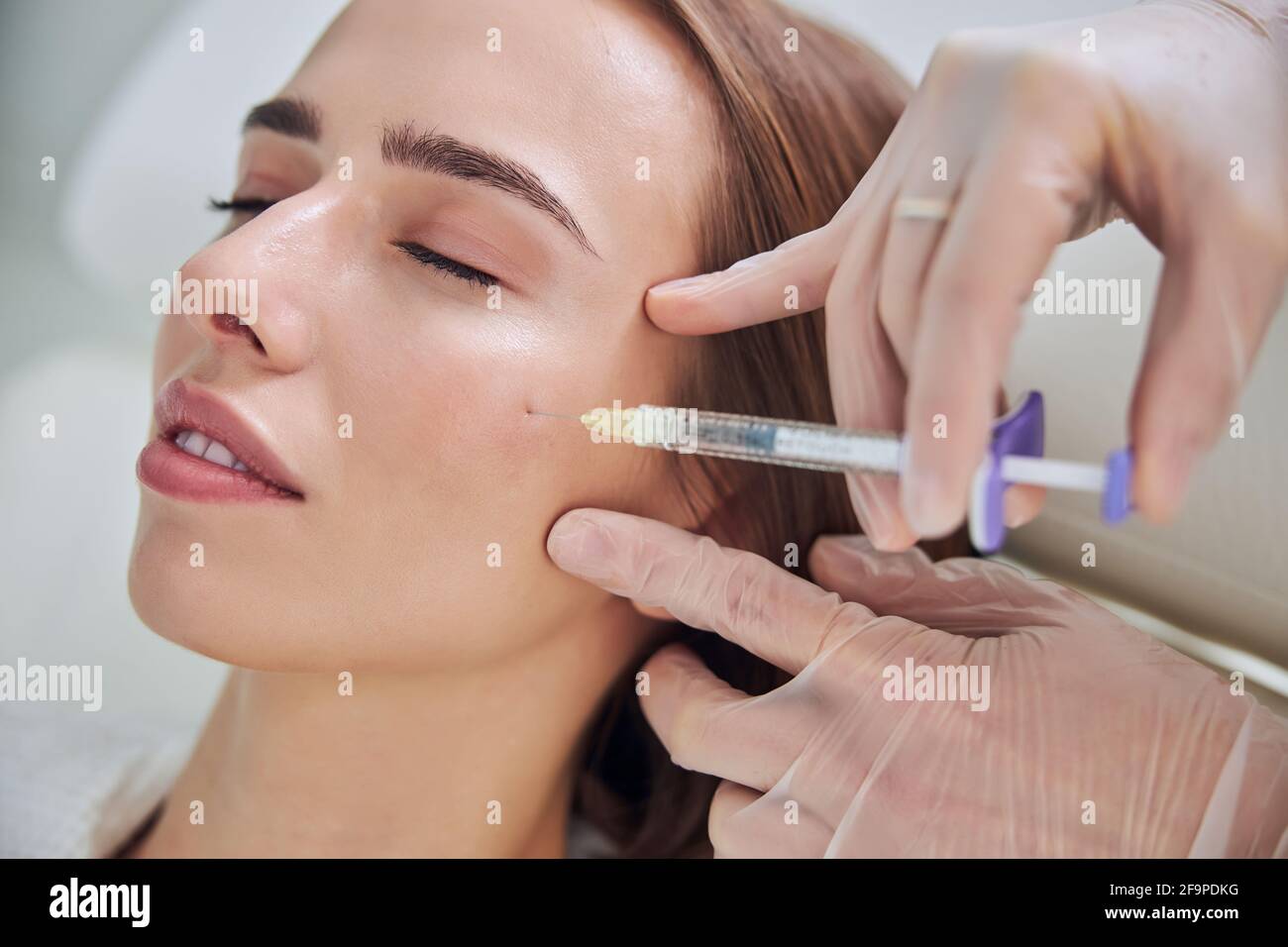 Beautiful elegant woman receiving plastic surgery injection on her face ...