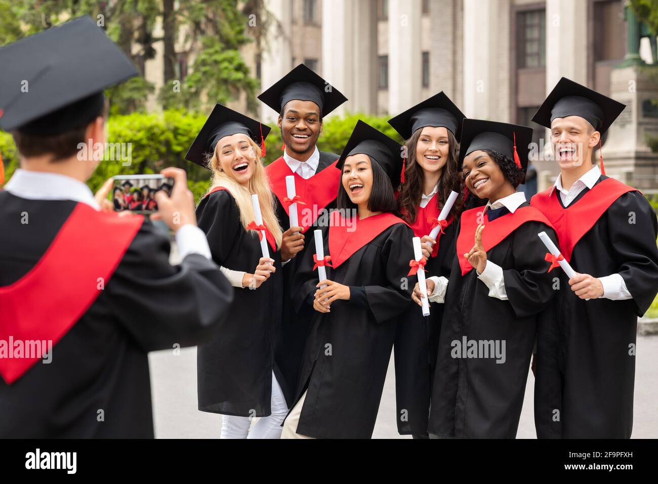 Positive international students celebrating graduation, taking photos ...