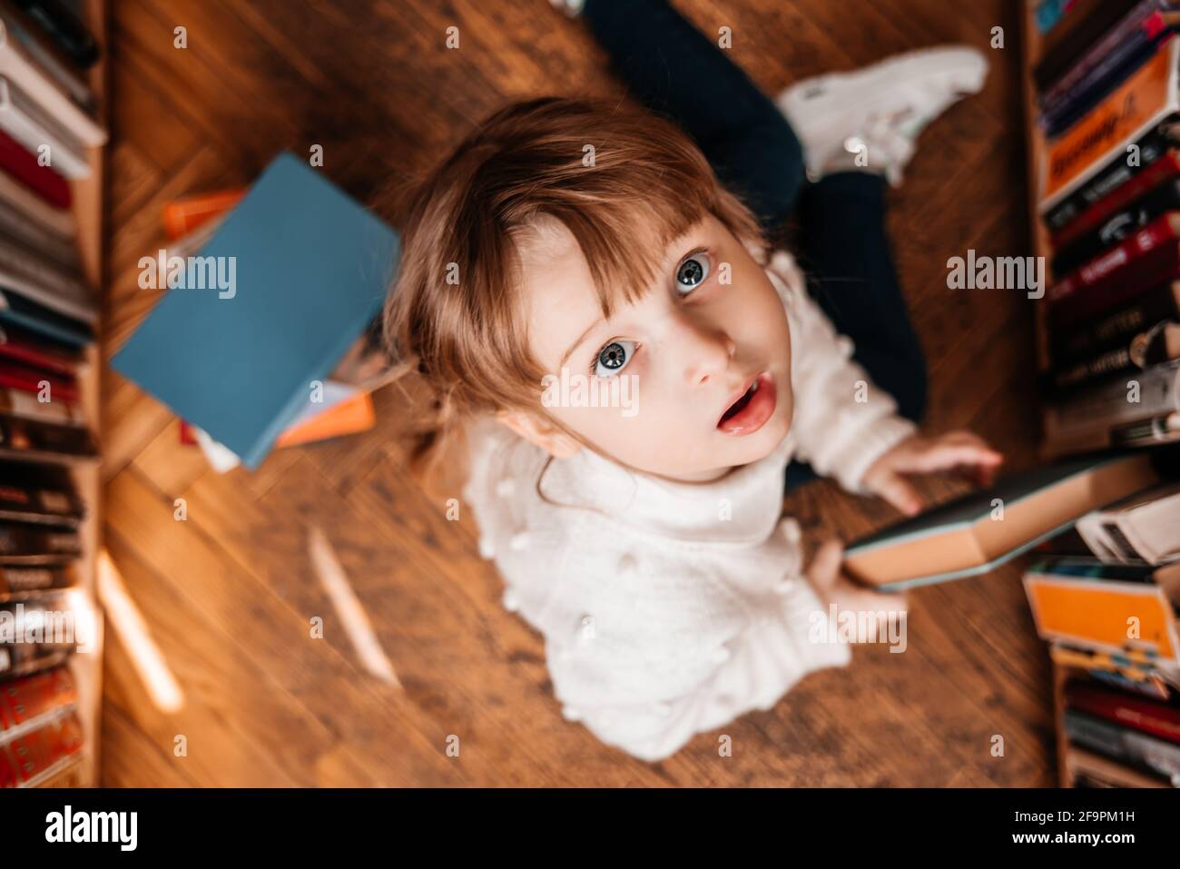 Baby girl in the library with books in her hands. cute toddler explores ...