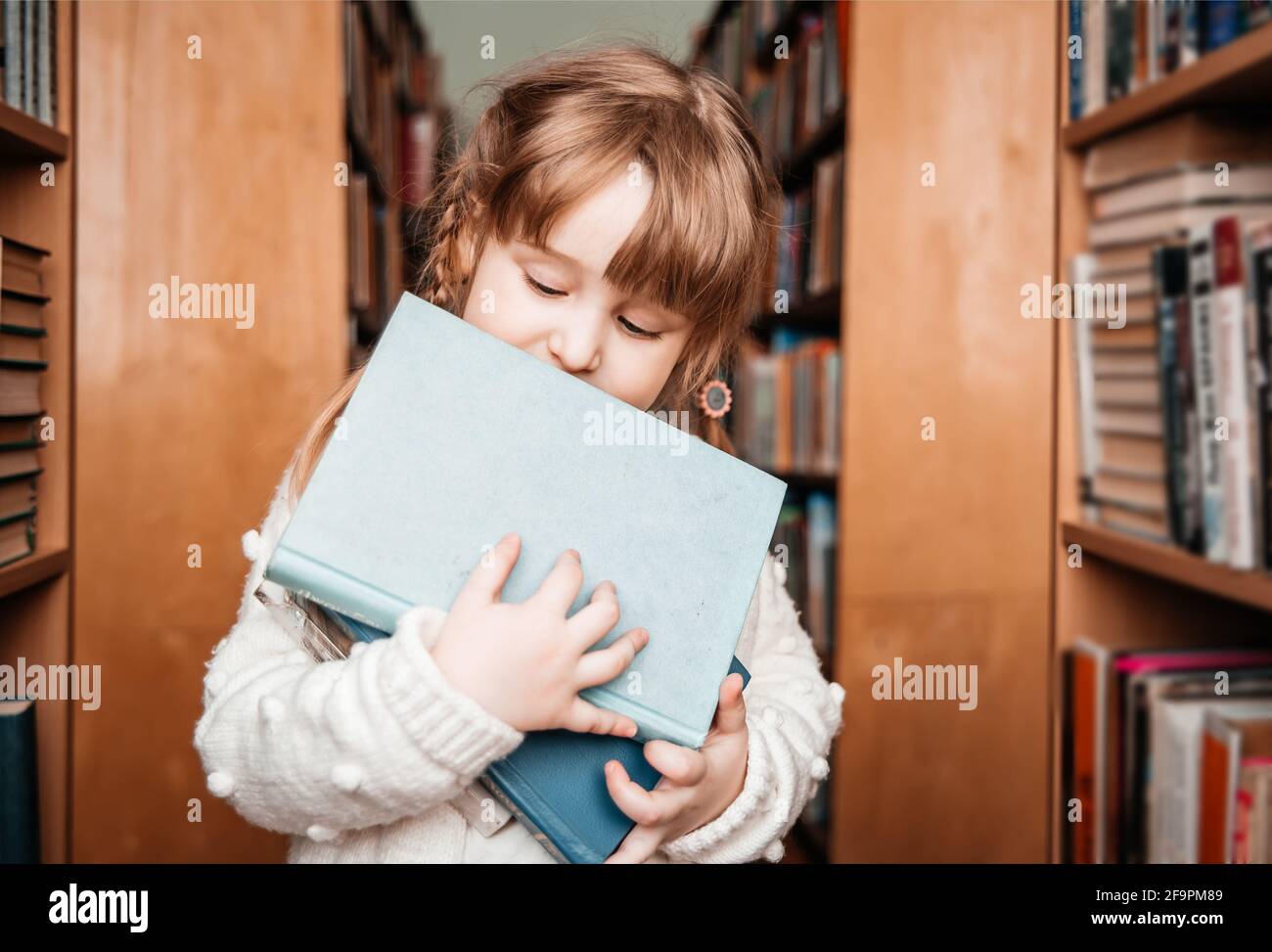 Baby girl in the library with books in her hands. cute toddler explores ...