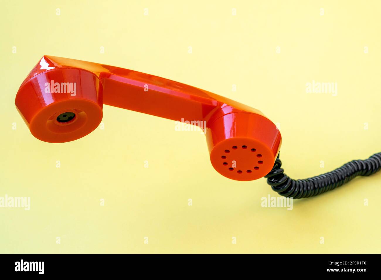 Retro orange telephone receiver on yellow background. Communication ...