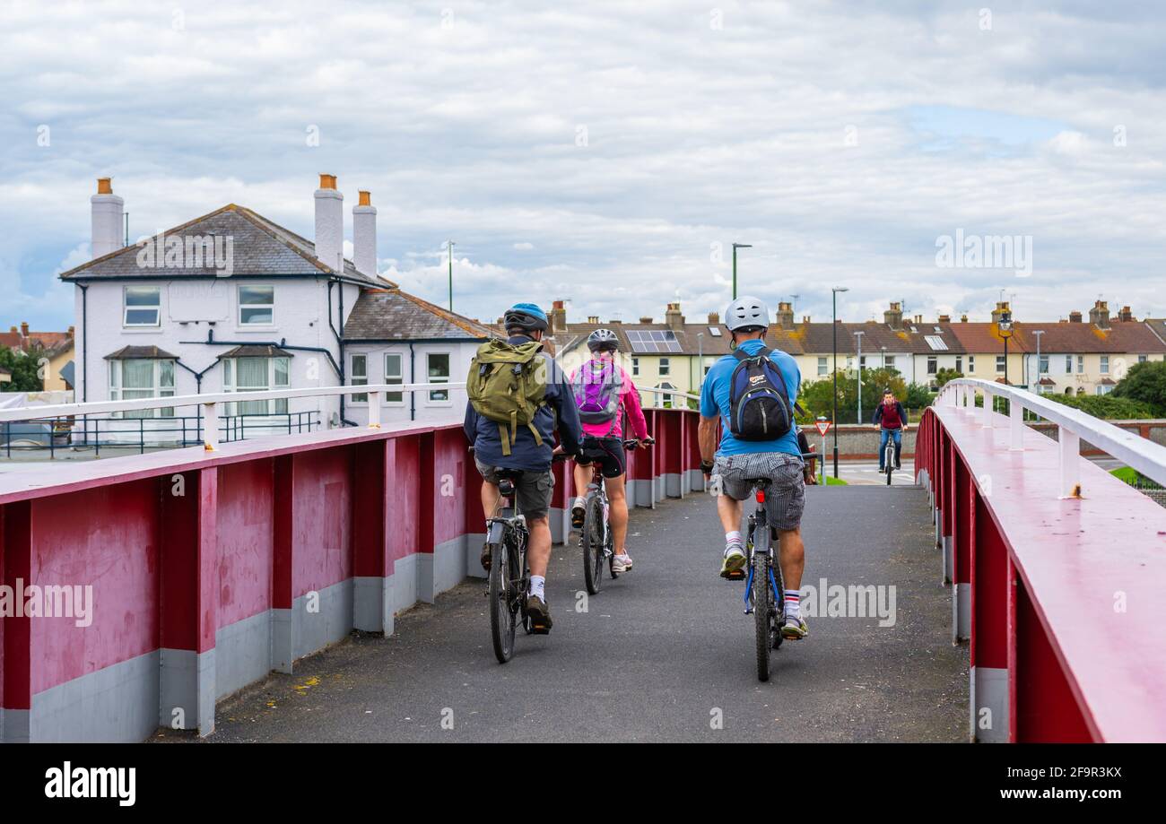 Small group of cyclists riding bicycles across a bridge. Cycling across ...