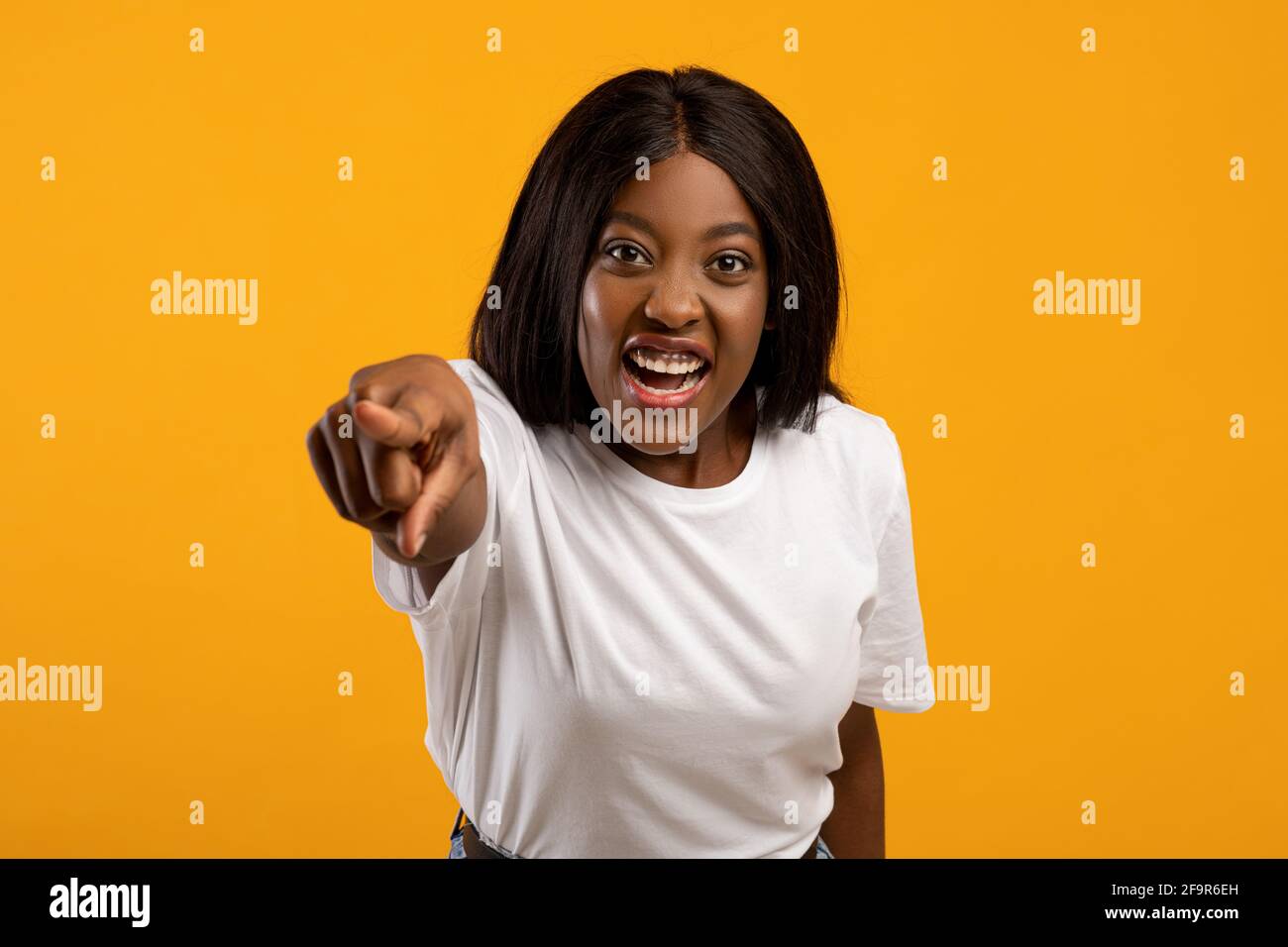 Angry black lady yelling and pointing at camera, yellow background ...