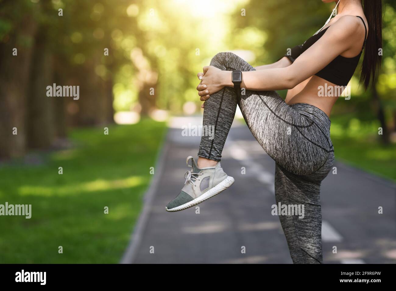 Female athlete getting ready for morning jogging in park, stretching ...