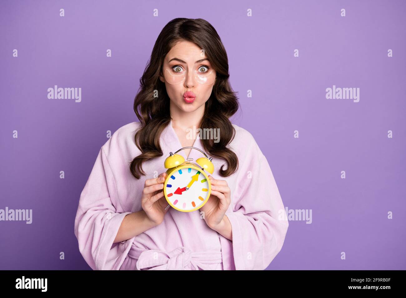 Photo of young girl pouted lips hold clock timer cosmetology procedure ...