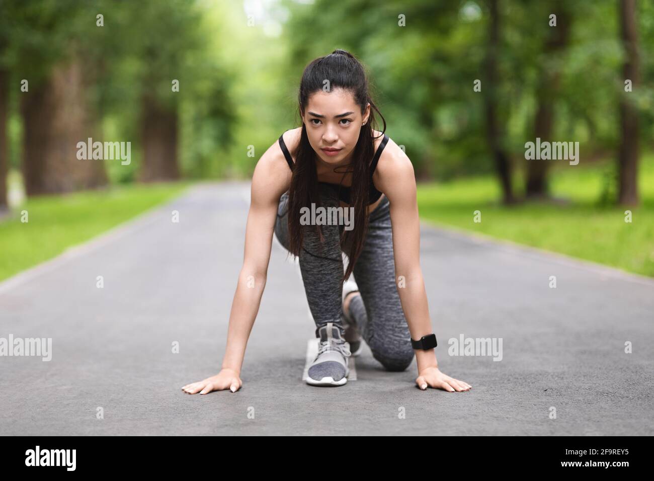 Motivated asian woman standing in starting position, ready for running ...