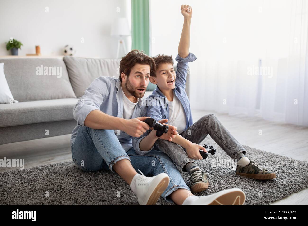 Father-son competition. Joyful boy winning dad in videogame and raising ...