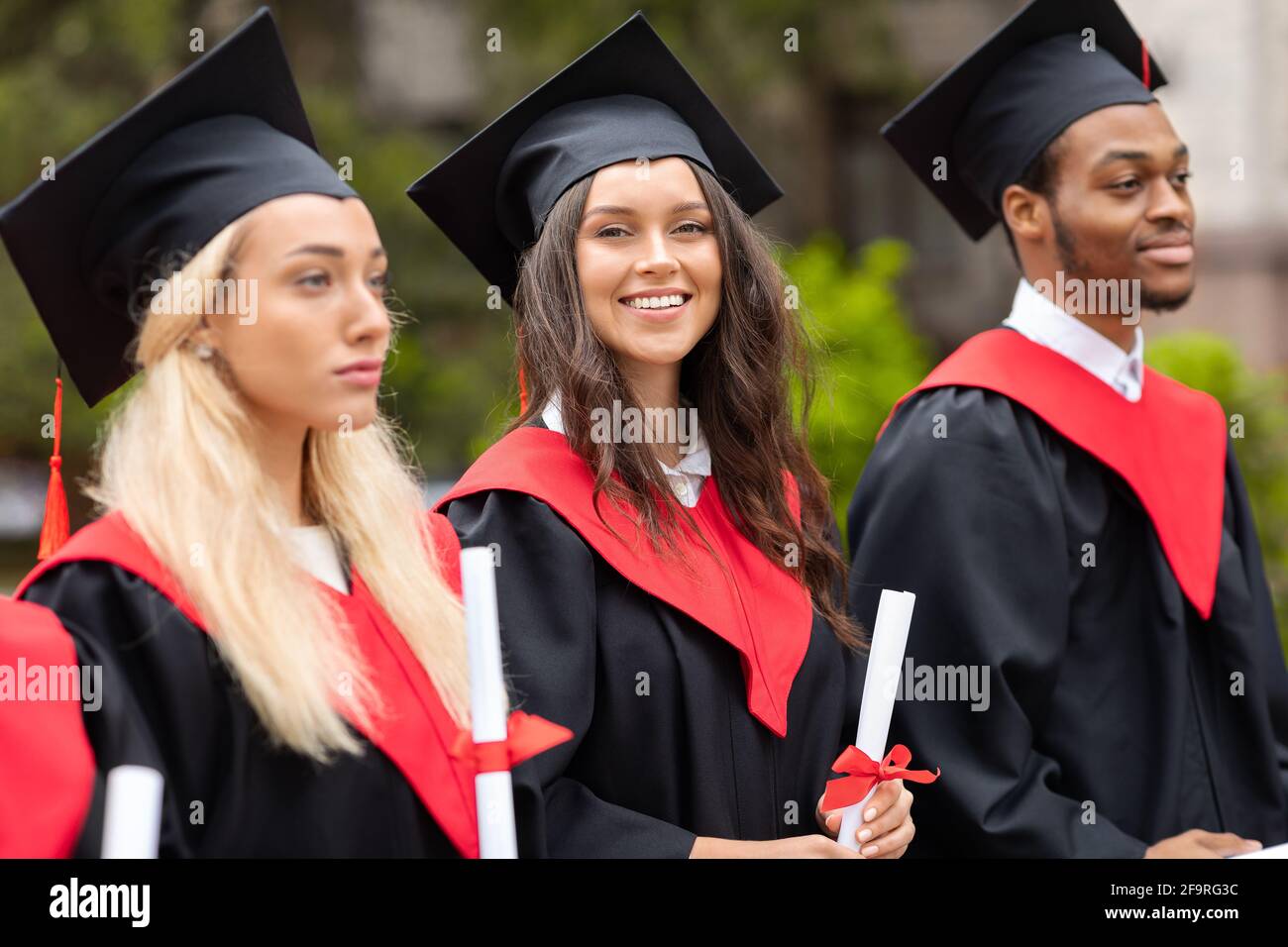 Attractive brunette lady standing among multiracial group of students ...