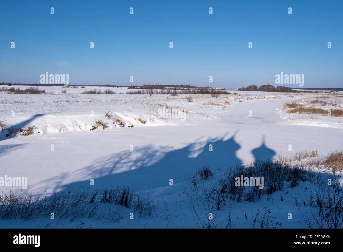 The shadow of church bells on the white snow of a frozen river on a ...