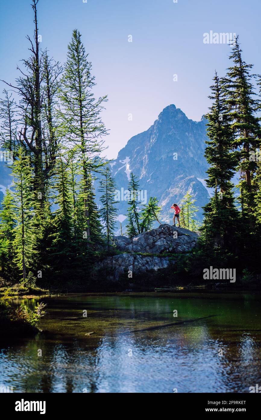 Female hiker top of the rock over alpine lake in North Cascades NP ...