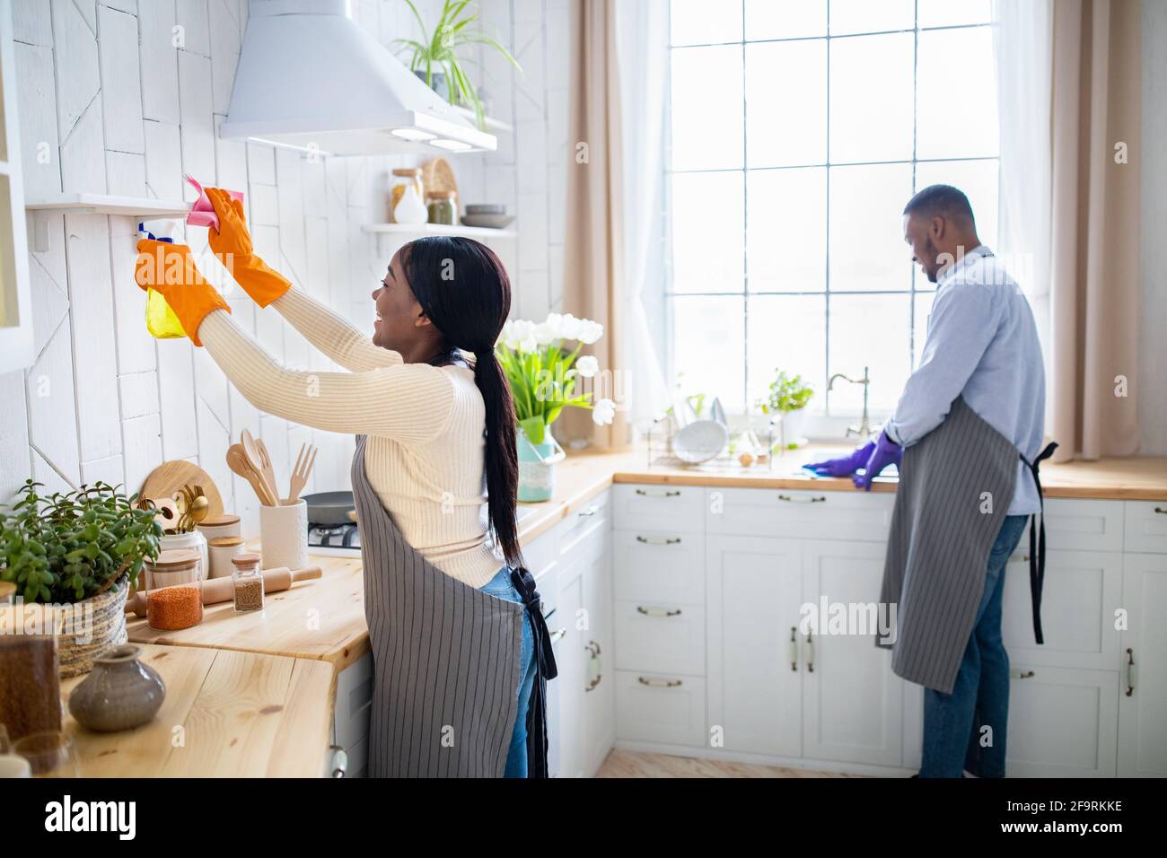 Millennial black couple cleaning their kitchen together, enjoying ...