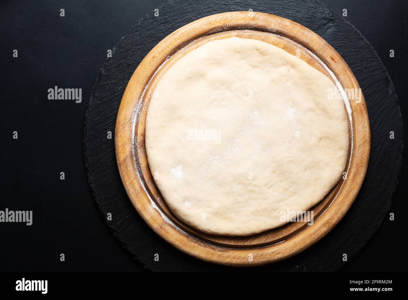 Food concept homemade pizza dough on wooden board on black background ...