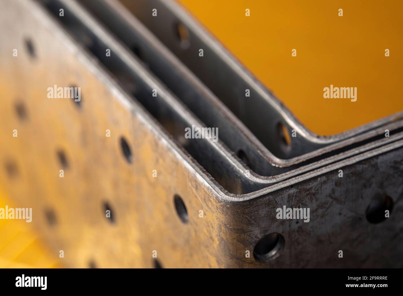 Stack of construction perforated steel angle brackets close up. Low ...