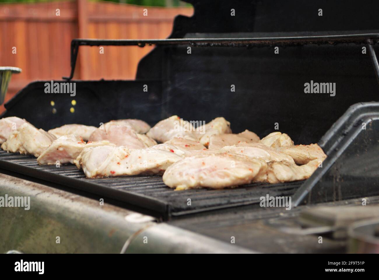 Cooking raw chicken on the grill for a backyard barbecue Stock Photo ...