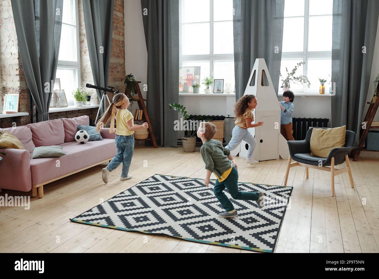 Group of children running around the room and playing together in the ...