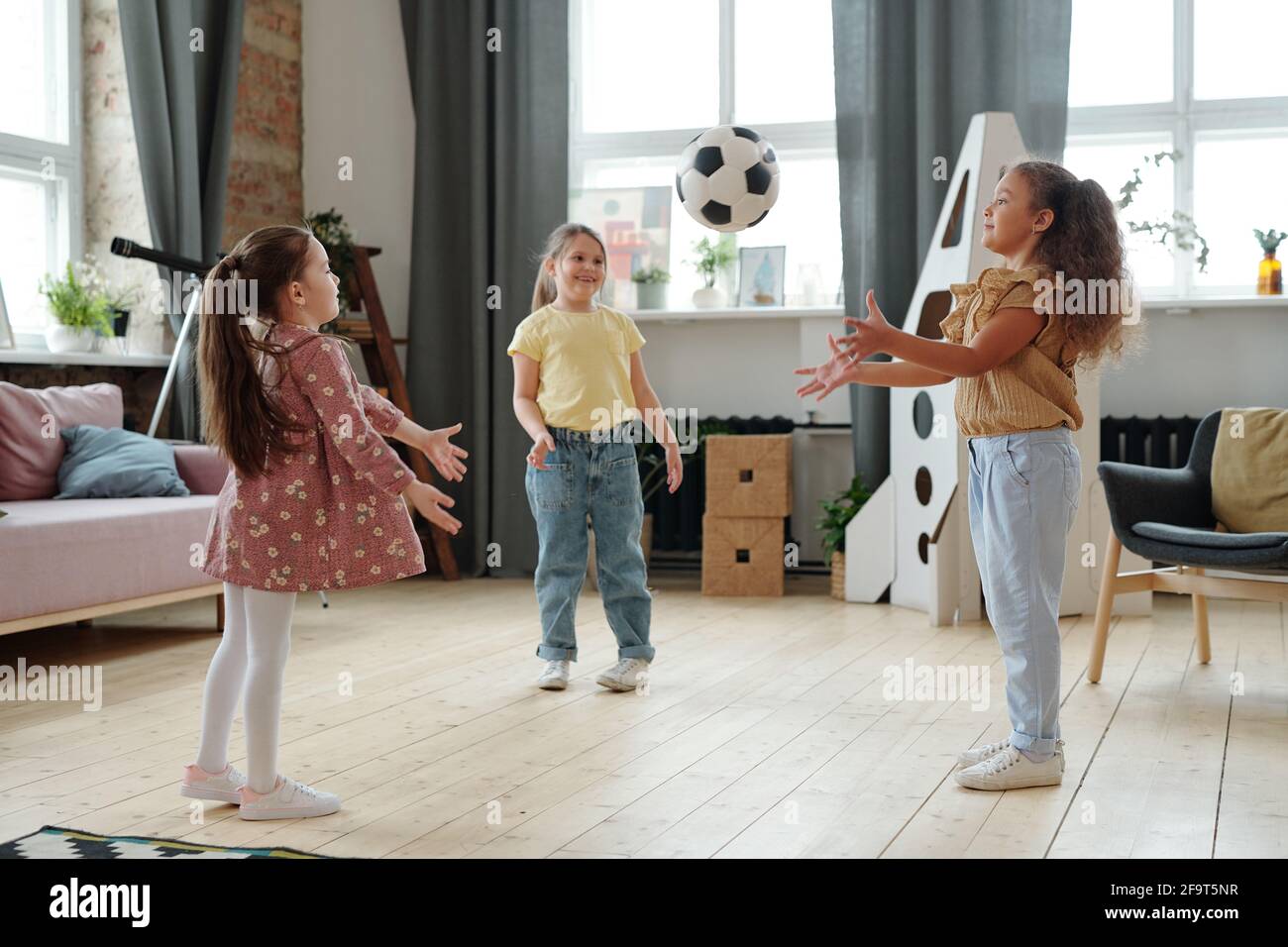 Group of friends playing ball together while standing in the room at ...