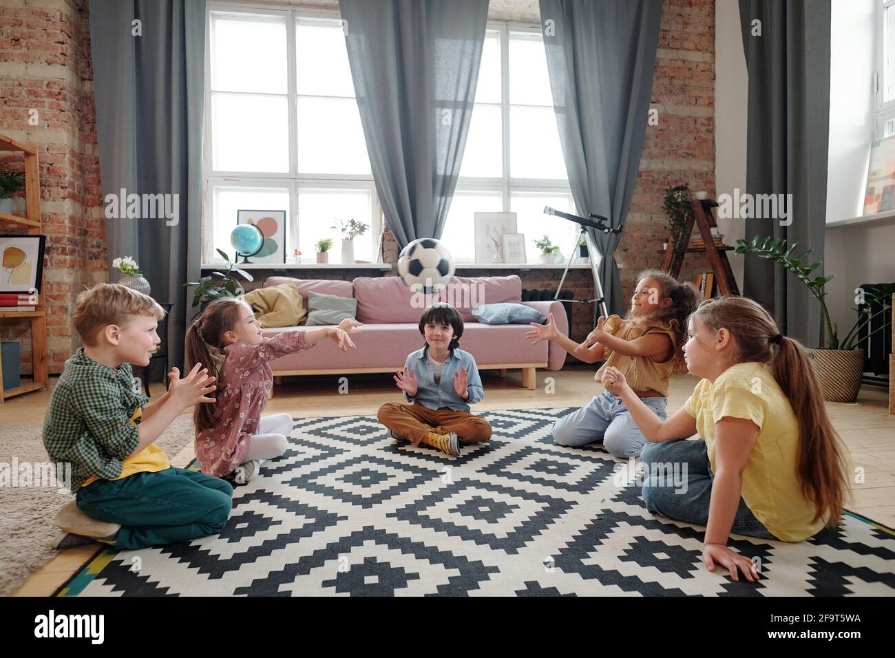 Group of friends sitting on the floor and playing ball together in the ...