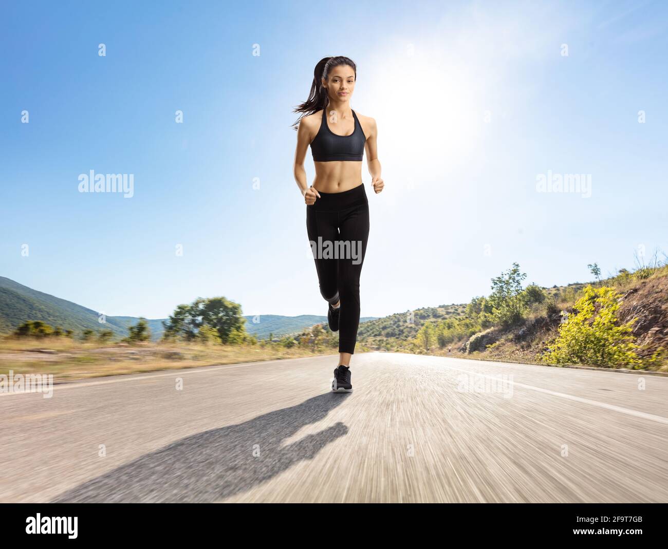 Full length portrait of a young slim female jogging outdoors on an open road Stock Photo - Alamy