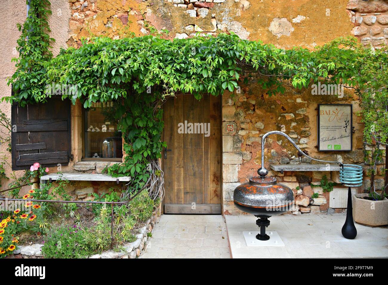 Provençal artisan distillery shop with a stone wall, wooden door and ...