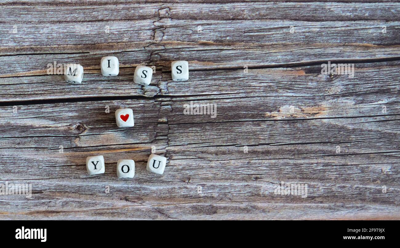 Dice forming the word "miss you" with a heart and on a wooden ...