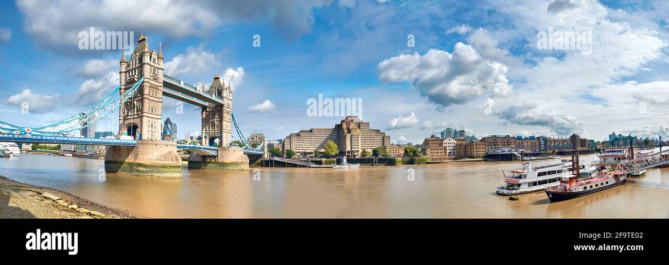 Tower Bridge on a bright sunny day with blue sky and clouds. Calm water ...