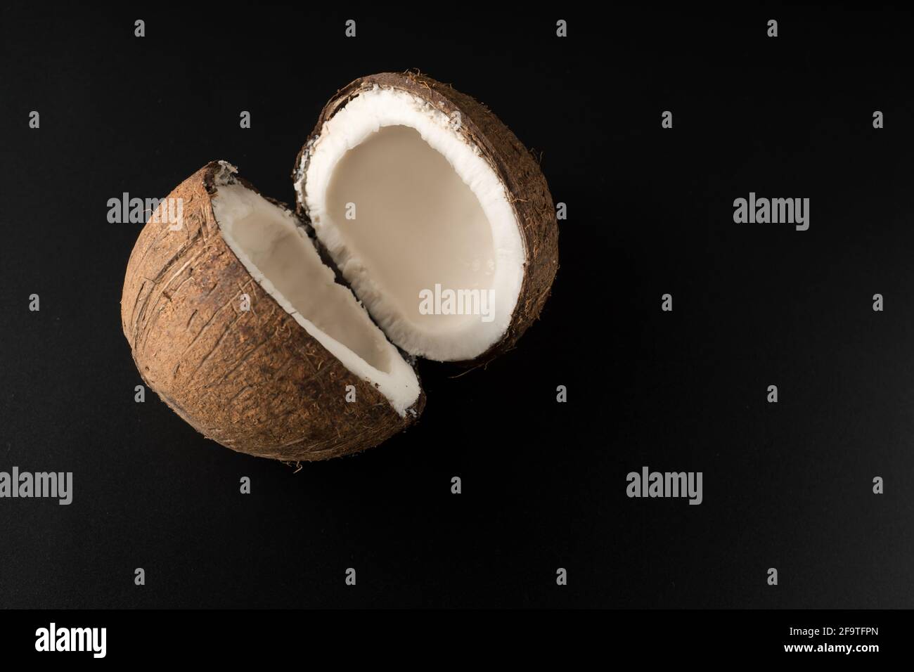 One ripe coconut divided into two parts, on a black background Stock ...