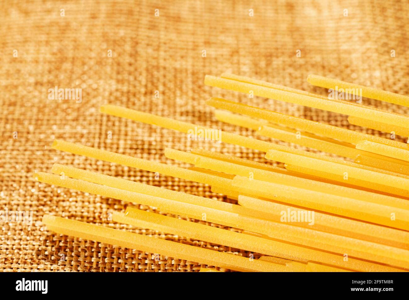 Dried pasta spaghetti on brown cloth ,long and thin solid cylindrical ...