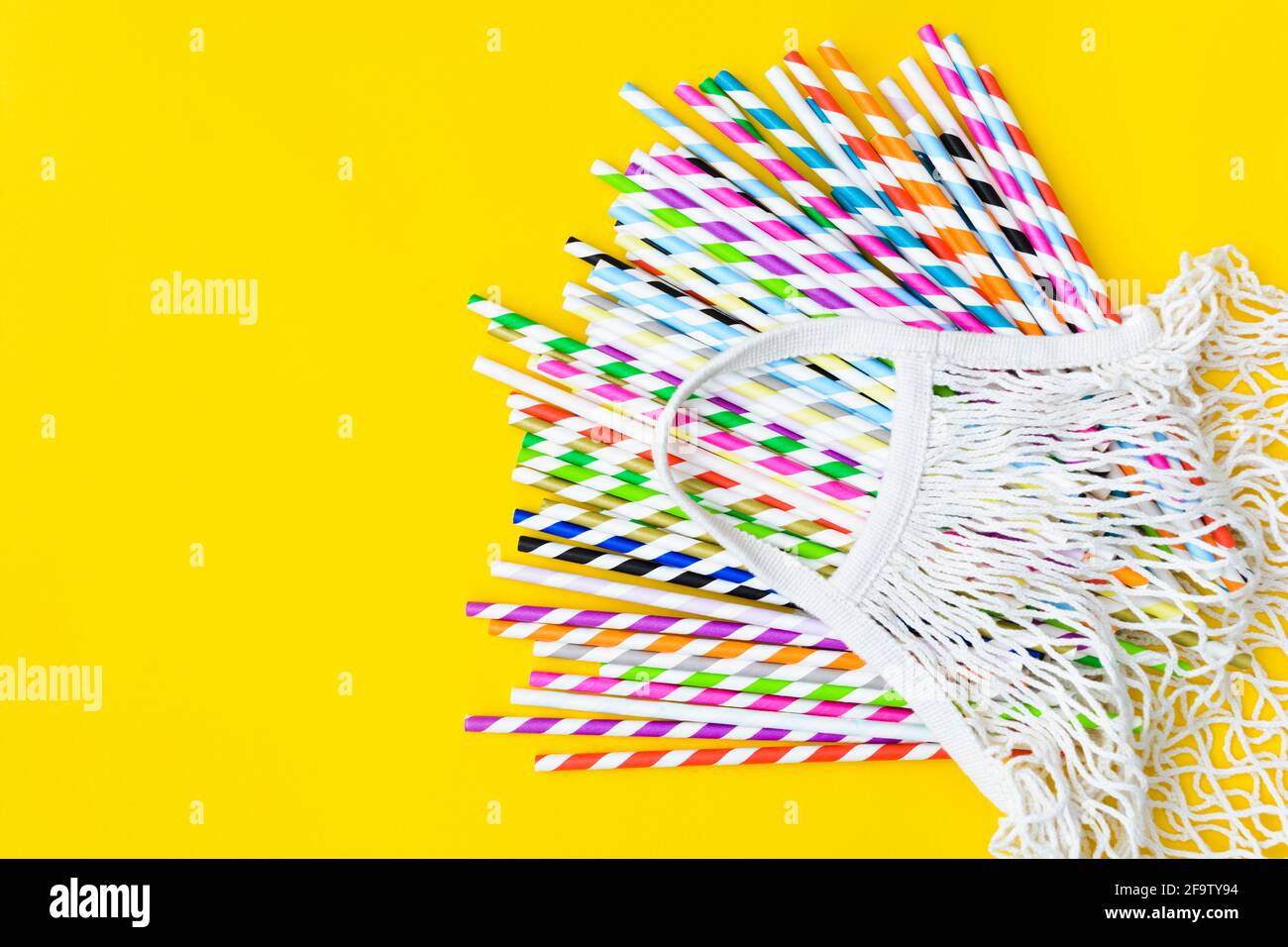 Colorful paper straws in material bag on yellow background with copy ...