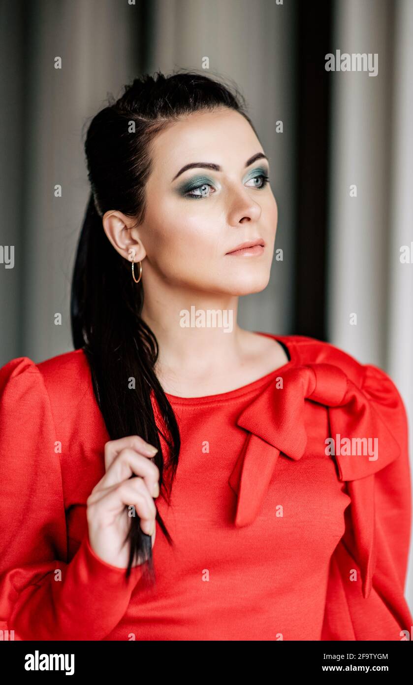 young lady in red evening dress in interior. brunette girl with ponytail in a red dress Stock ...