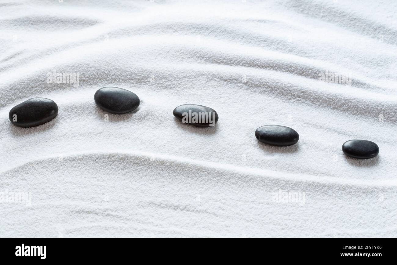 Zen pebbles on white sand pattern Stock Photo - Alamy