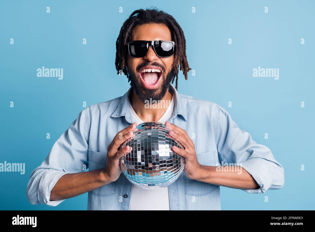 Portrait of nice cheerful cool guy holding in hands glossy disco ball ...